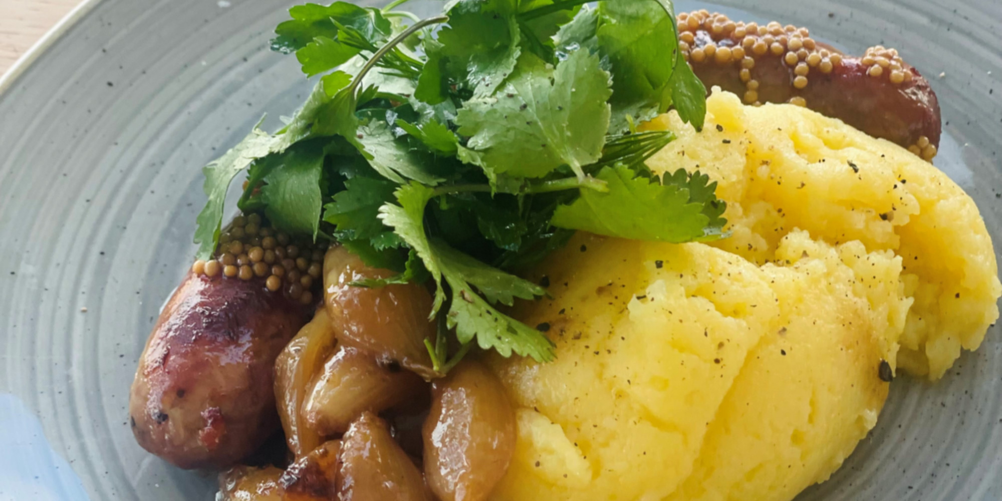 Saucisse grillée, purée de pomme de terre et confit d'oignons grelots ...